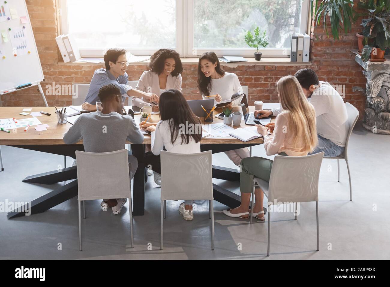 Friendly business team sitting around table, having meeting Stock Photo ...
