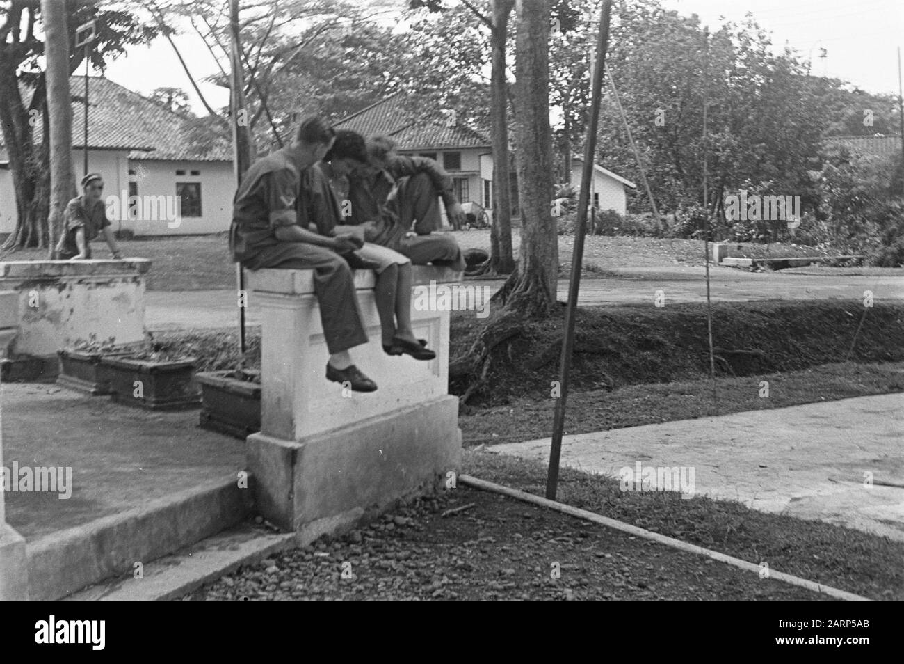 Two soldiers sitting with a girl on a balustrade on the grounds of ...