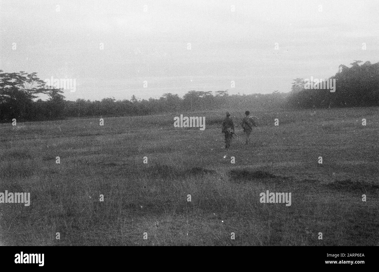 Two soldiers walking across an open field Annotation: DJK Date: 1947/01 ...