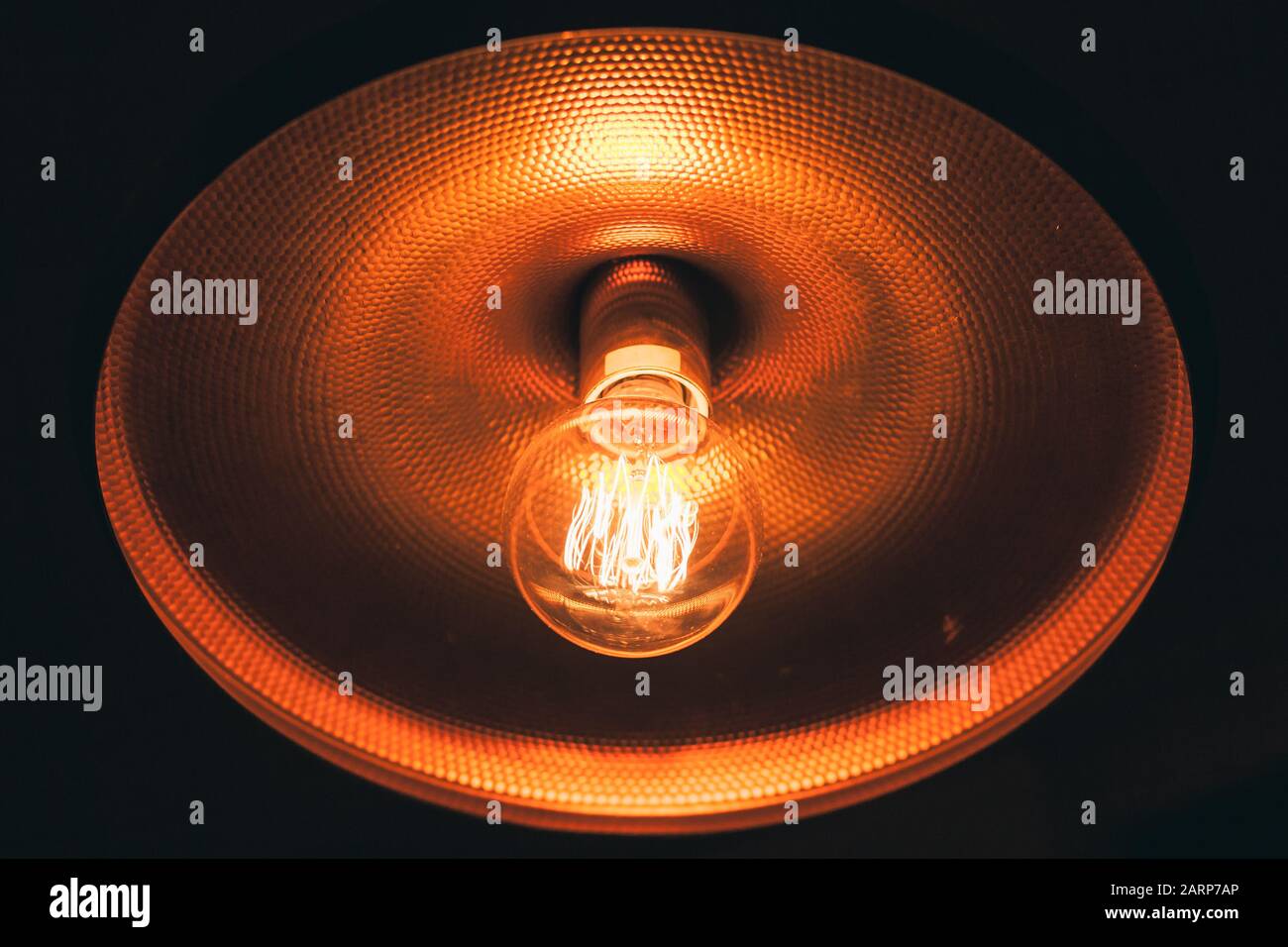 Vintage stylized tungsten lamp in a shiny round lampshade glowing in ...