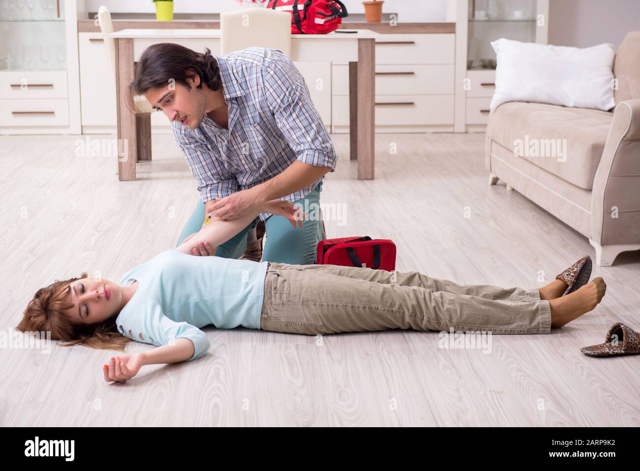 The young couple in first aid concept at home Stock Photo - Alamy