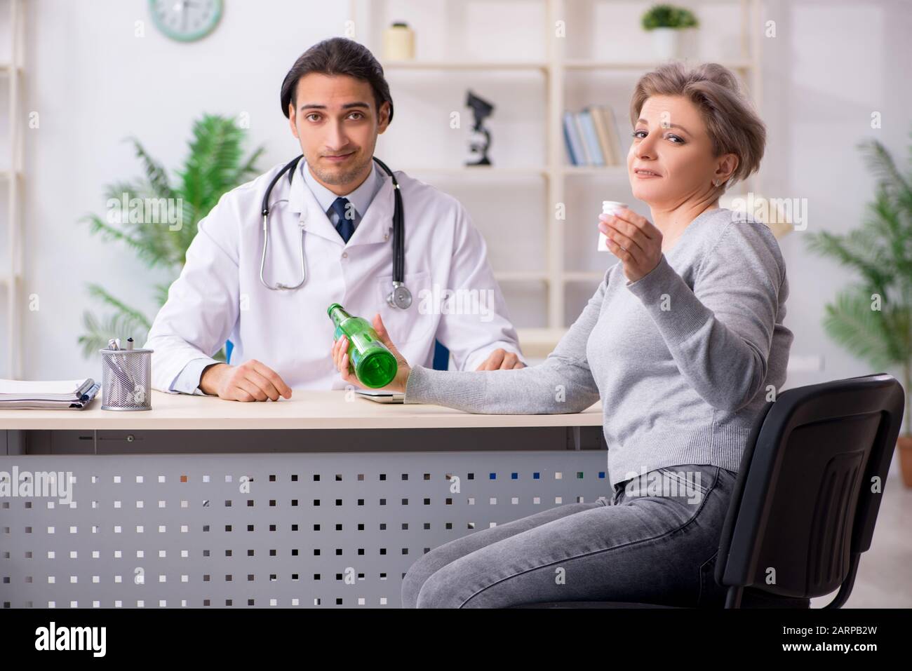 The female alcoholic visiting young male doctor Stock Photo - Alamy