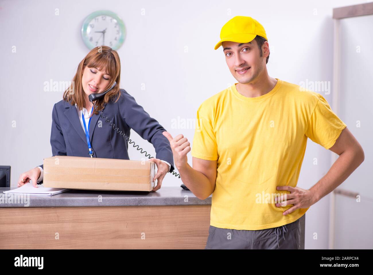 The young male courier delivering box to hotel's reception Stock Photo ...