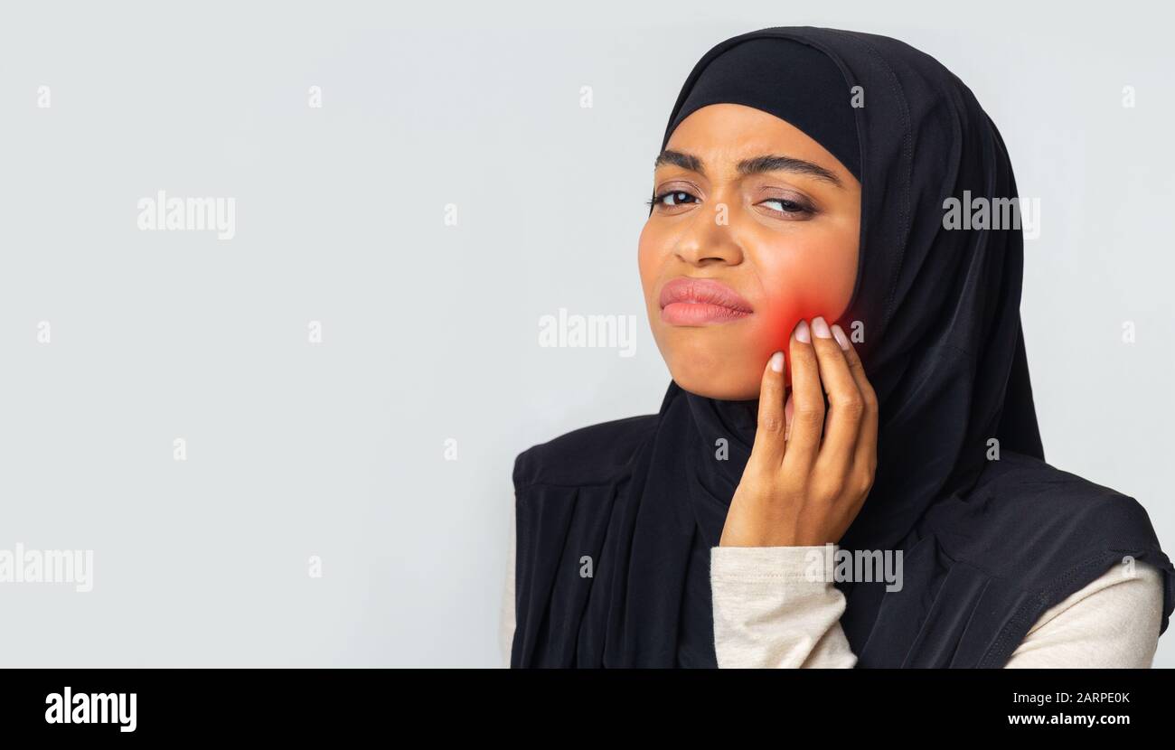 Black muslim girl having toothache, touching cheek with red inflamed ...