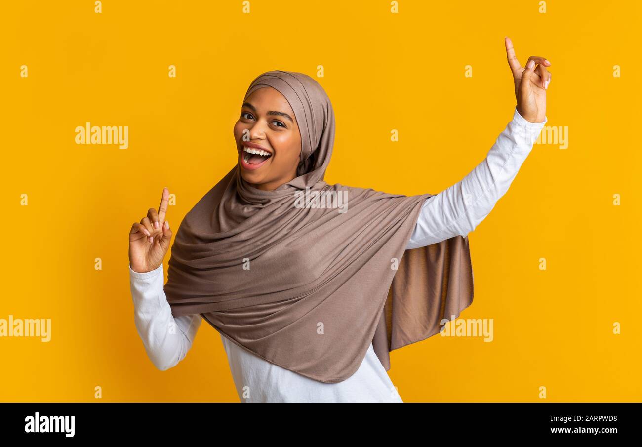 Joyful muslim girl in hijab dancing and singing with raised hands Stock ...