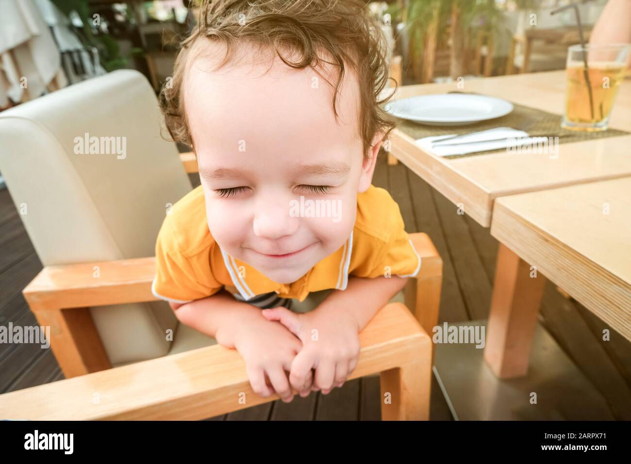 A funny little boy squints his eyes. Curly, tousled brown hair. A child ...