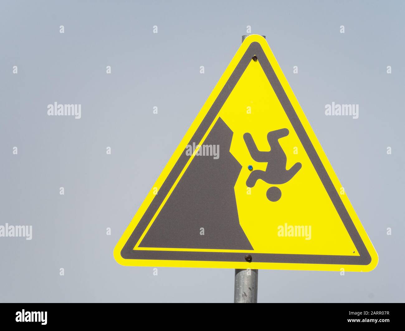 Yellow triangular sign with a man falling from a cliff on gray ...