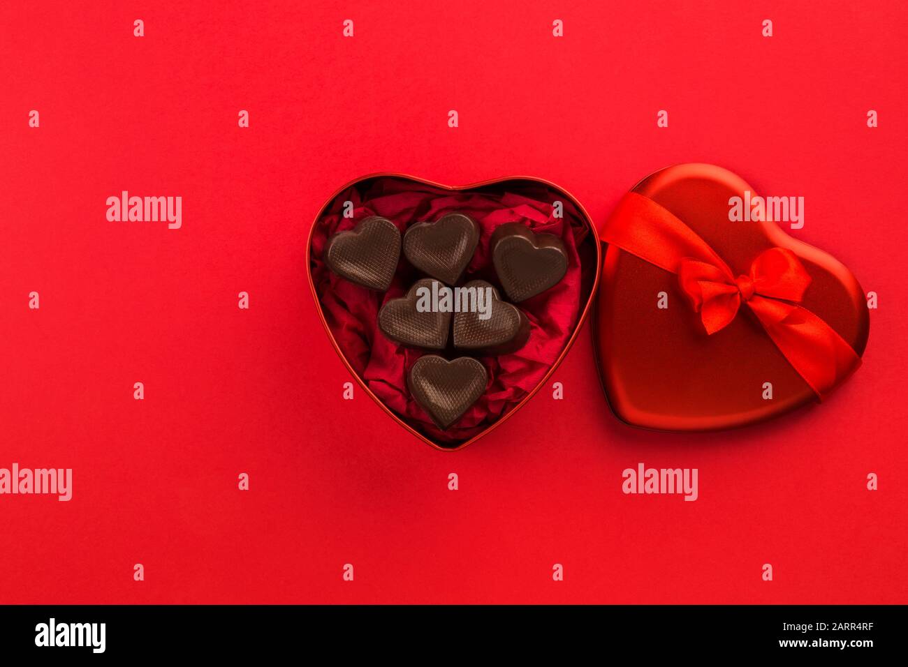 Red heart-shaped box with chocolate candy on red background Stock Photo ...