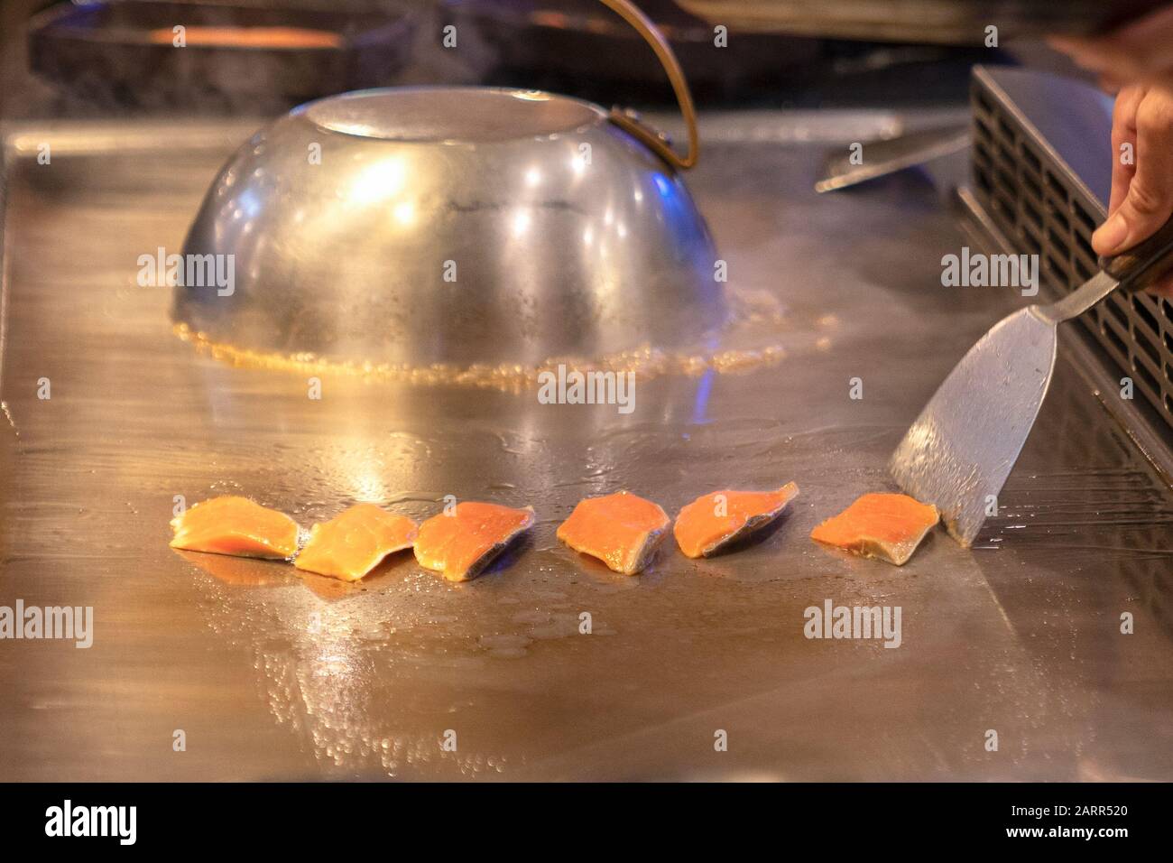 frying fish on a roasting surface, turning it over with a spatula in a ...