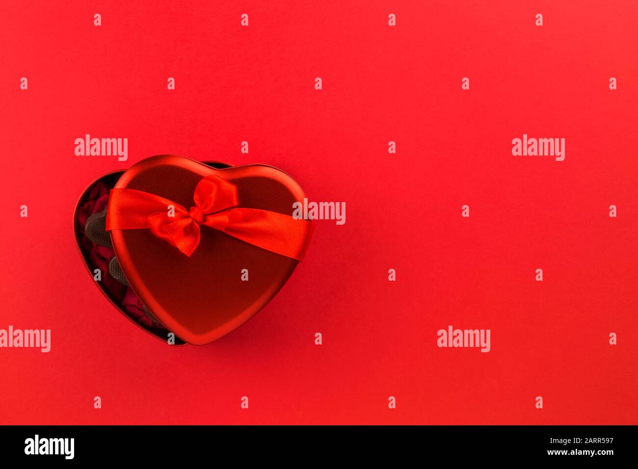Red heart-shaped box with chocolate candy on red background Stock Photo ...