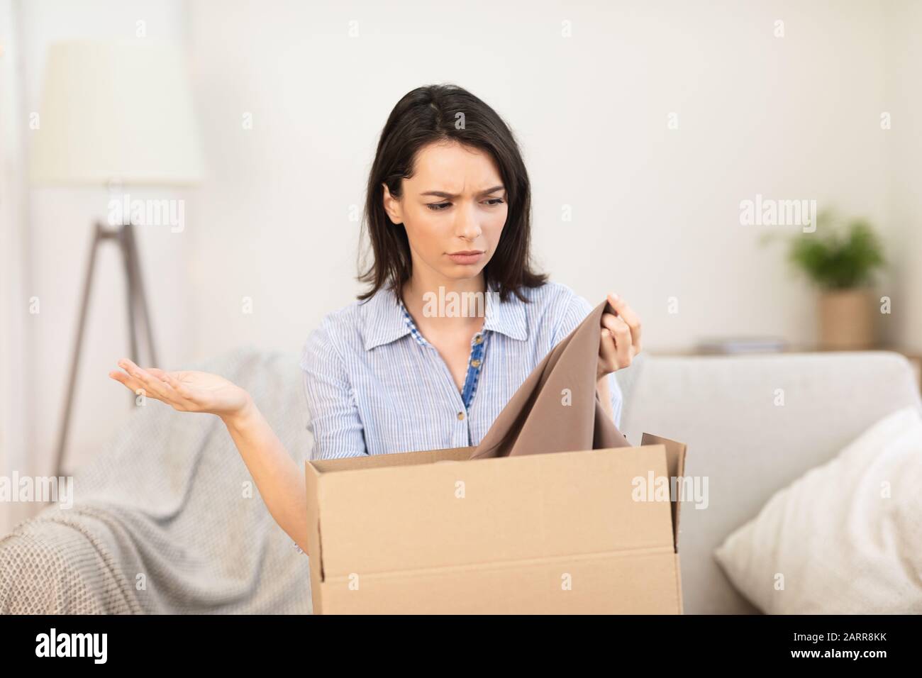Sad young girl packing clothes for delivery Stock Photo - Alamy