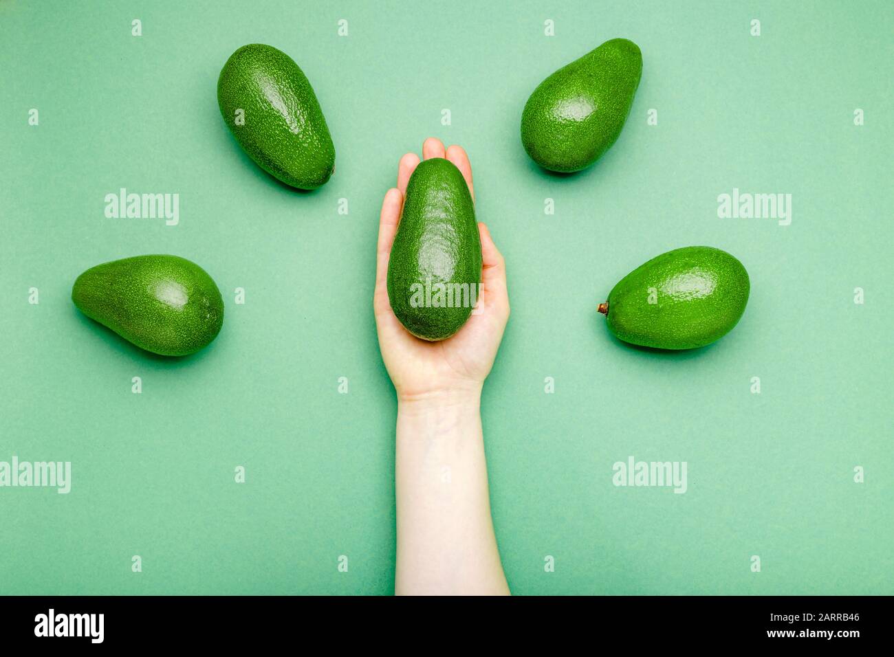 Fresh ripe organic green avocado in female hand on color background ...