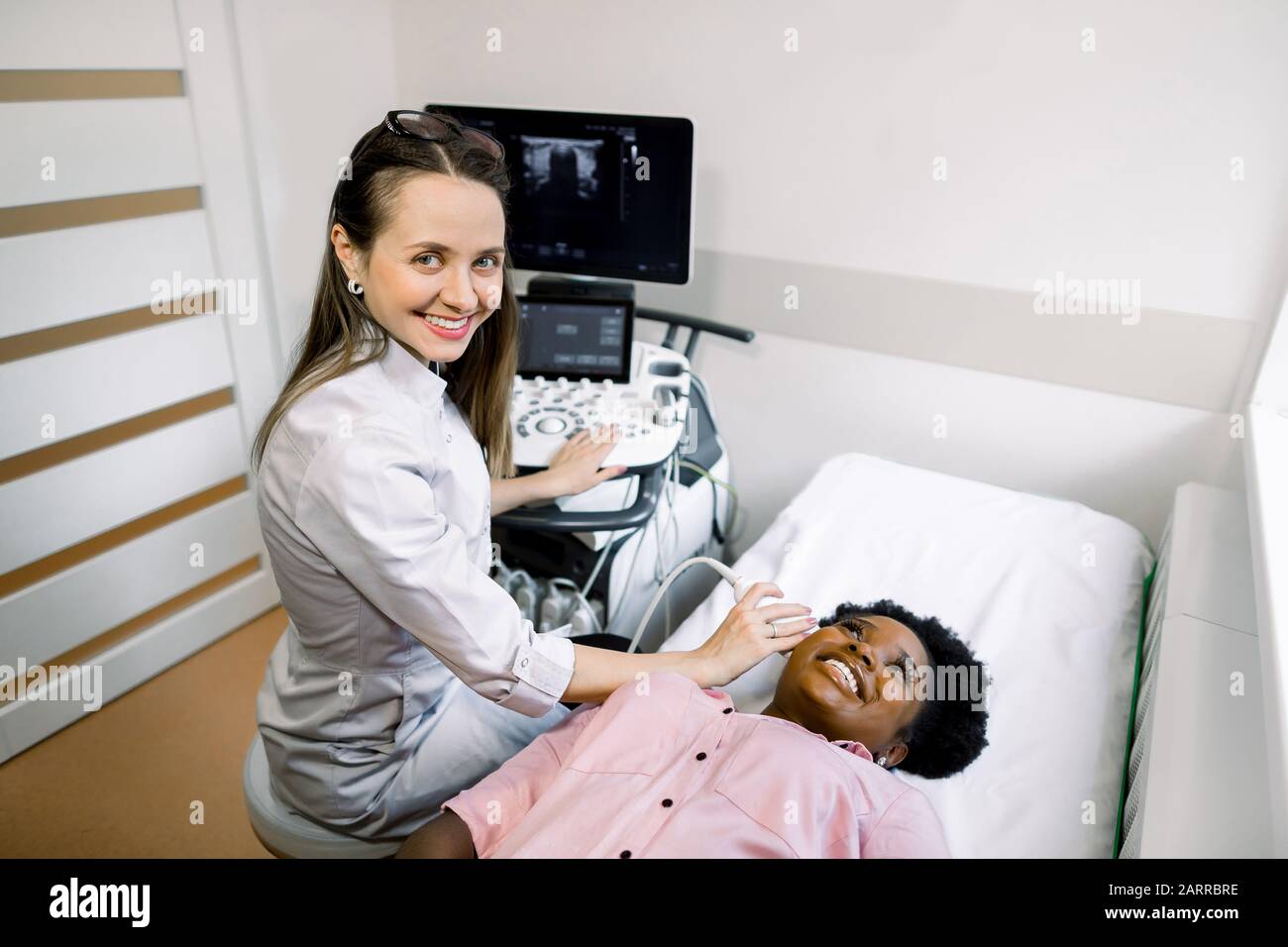 Young African woman undergoing ultrasound scan of her neck and cheeks ...