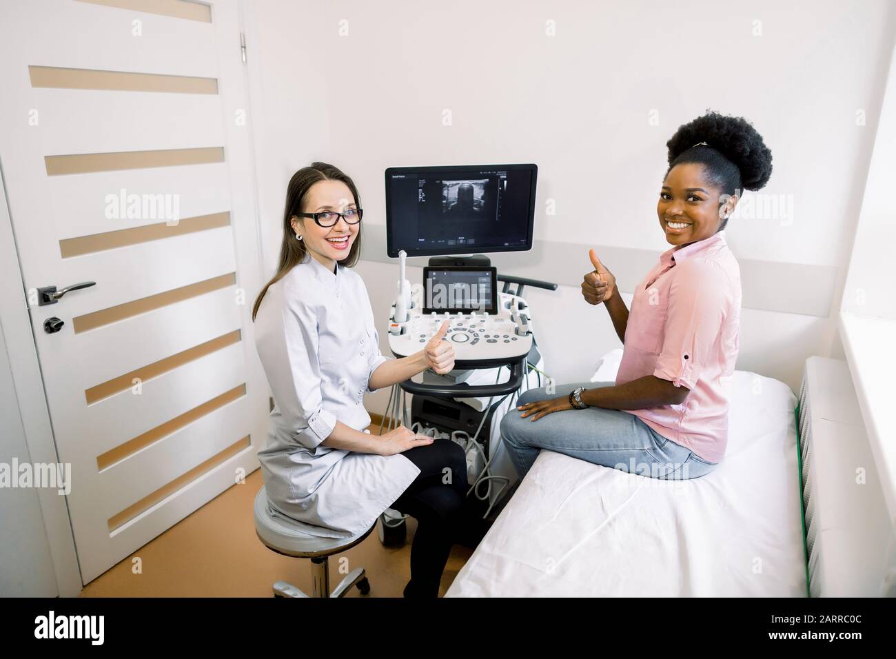 Portrait of smiling doctor and happy woman patient, looking at camera ...