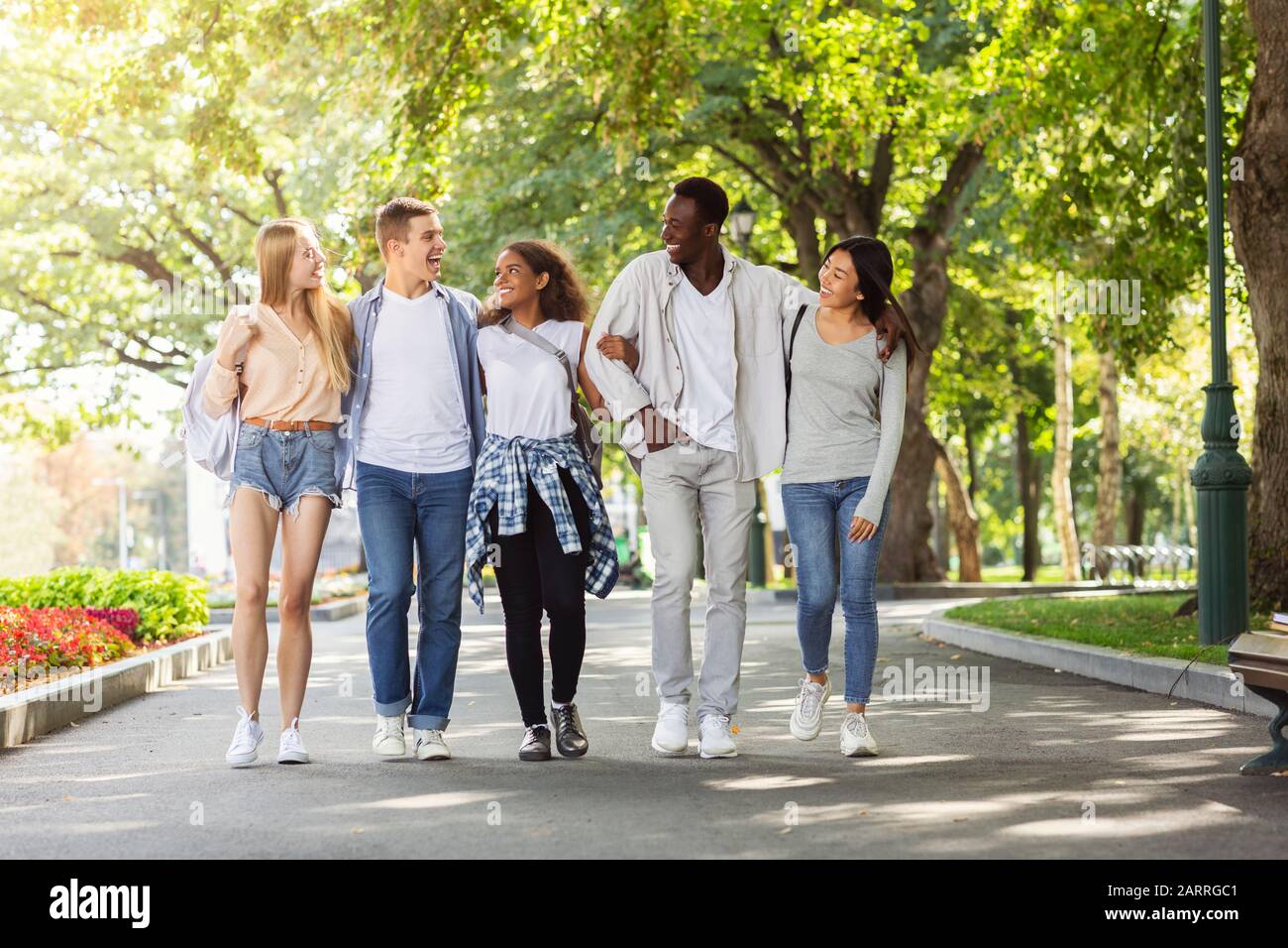 Students walking in park after university, chatting and having fun ...