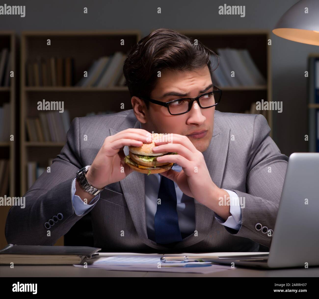 The businessman late at night eating a burger Stock Photo - Alamy