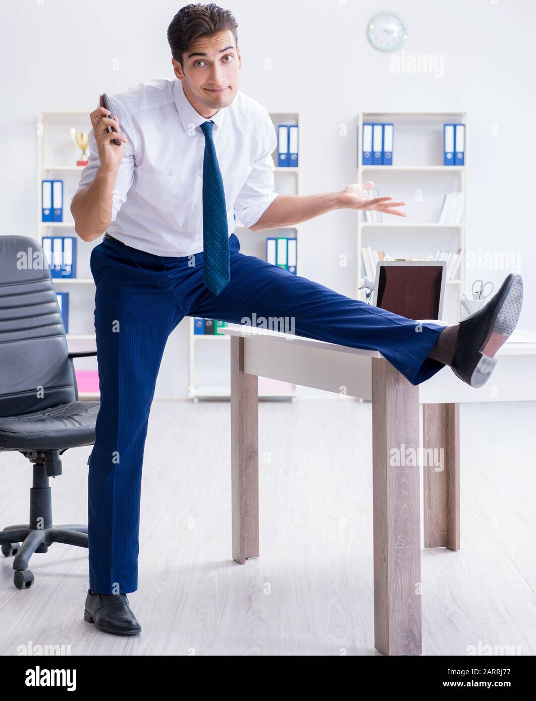 The young businessman doing sports stretching at workplace Stock Photo ...