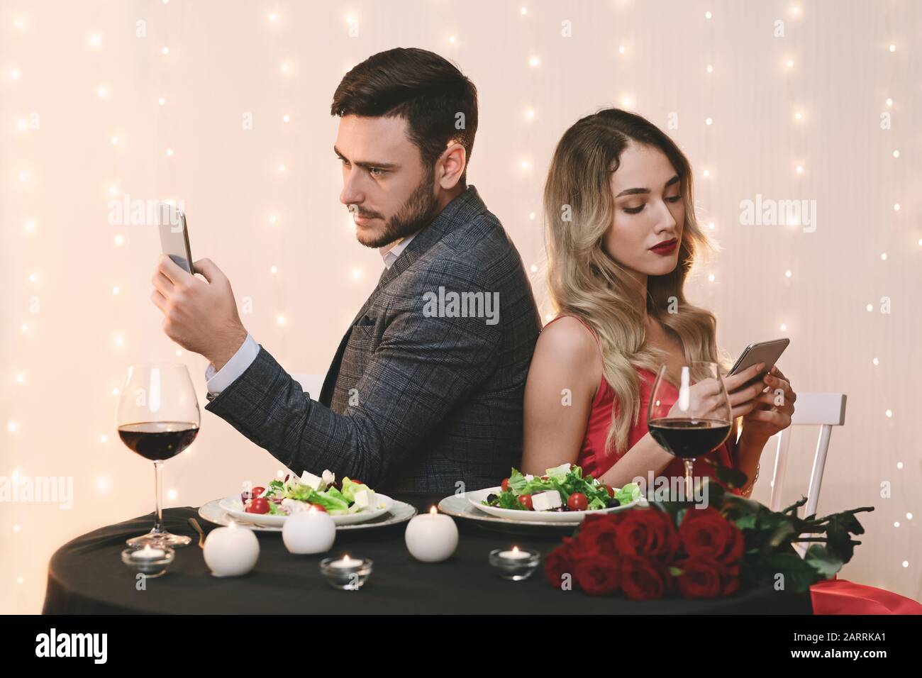 Bored Couple Using Smartphones Sitting Back To Back On Romantic Date