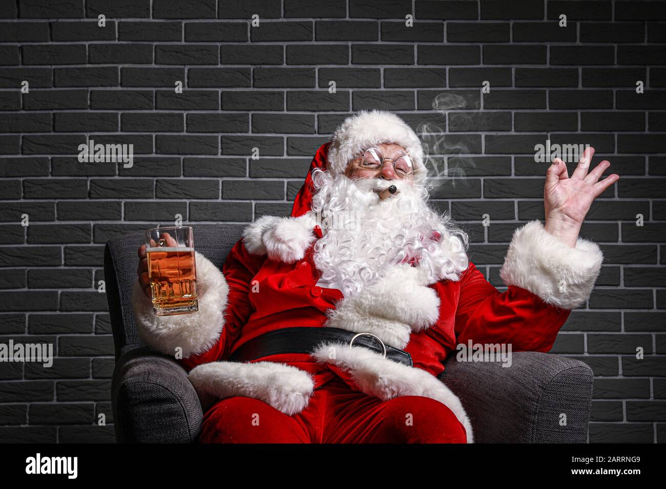 Funny drunk Santa Claus showing OK while sitting in armchair against ...