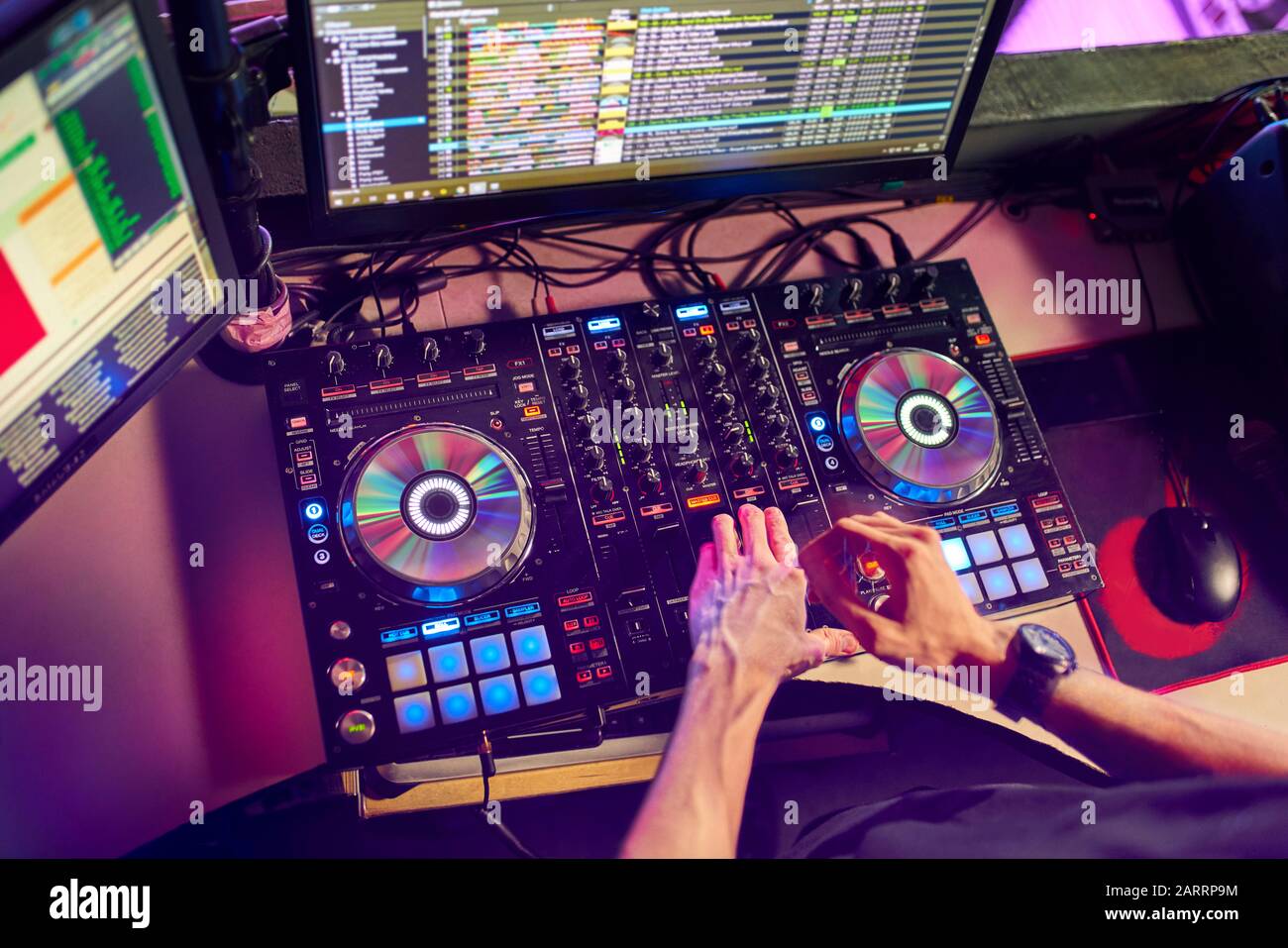 Dj mixes the track in the nightclub at party. In the background laser ...