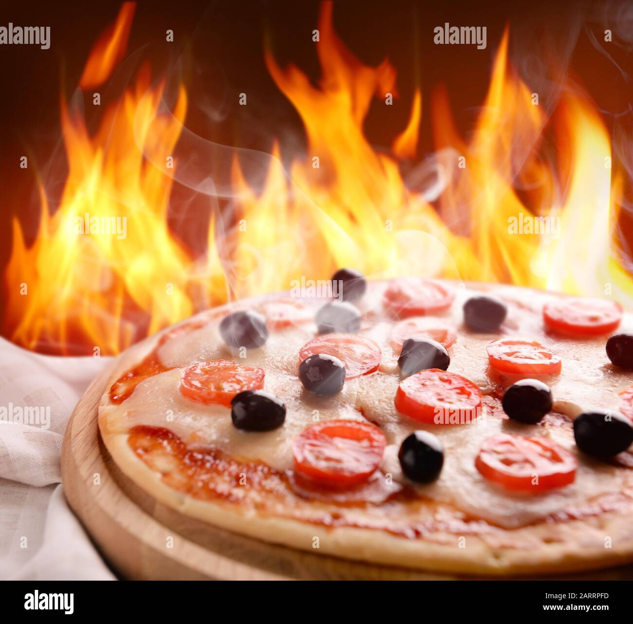 Hot pizza with burning flame on board against color background Stock ...