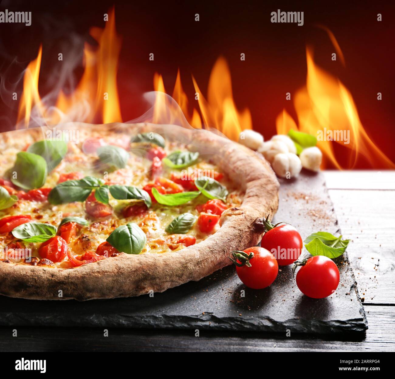 Hot pizza with burning flame on table against color background Stock ...