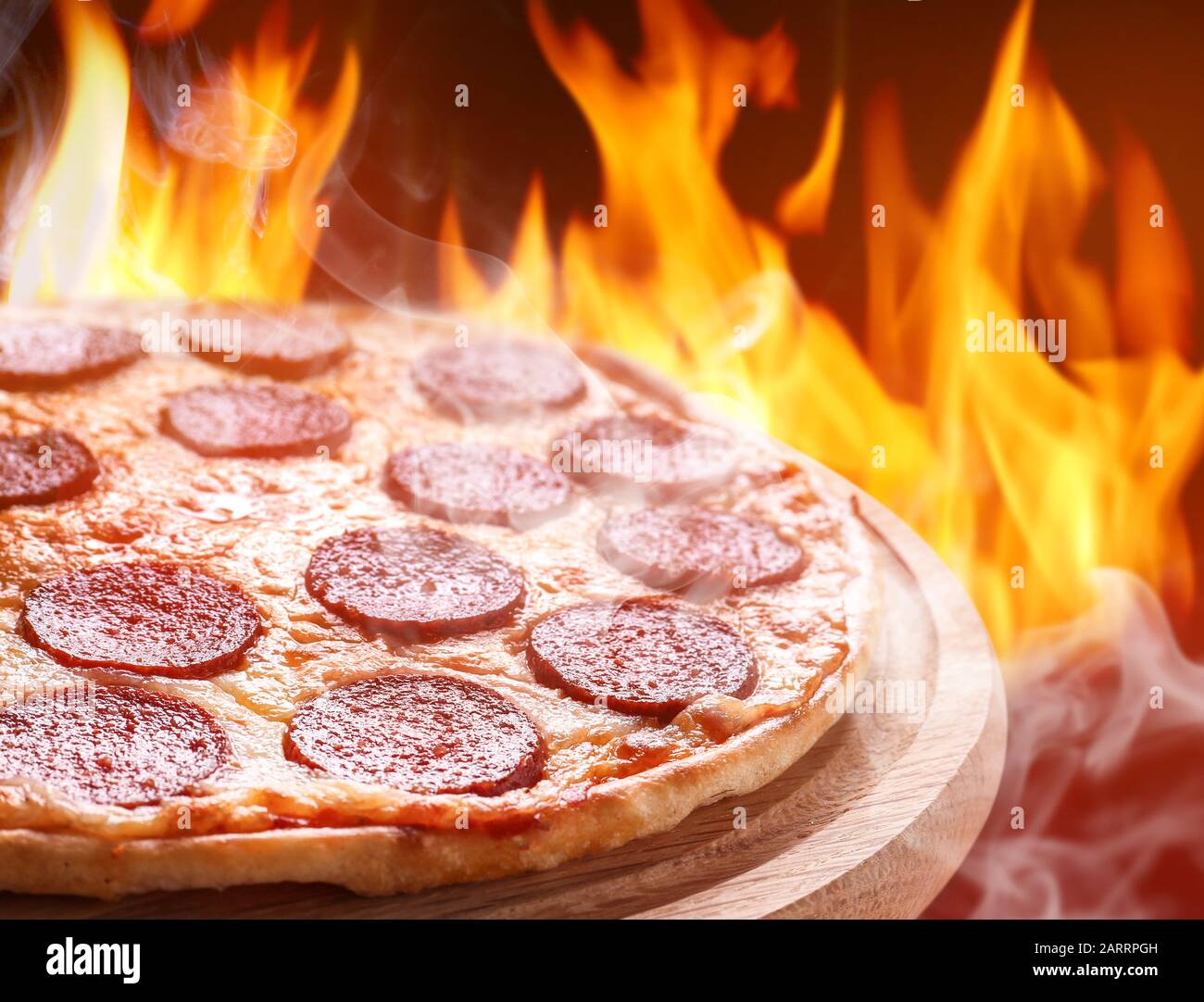Tasty hot pizza on wooden board with burning flame Stock Photo - Alamy