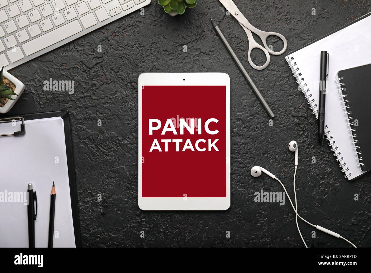 Tablet computer with text PANIC ATTACK, PC keyboard and stationery on ...