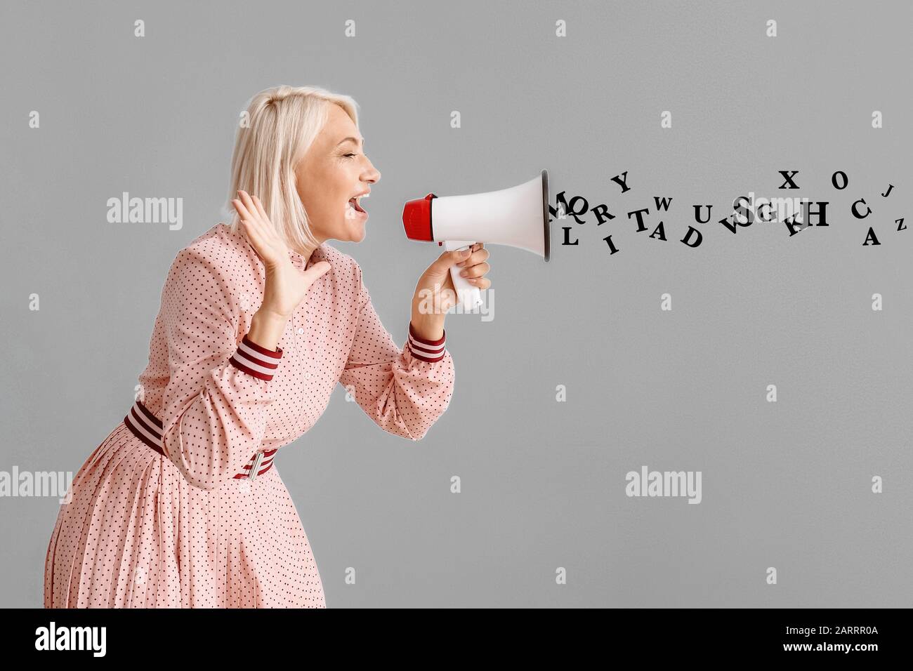 Middle-aged language school teacher with megaphone on grey background ...