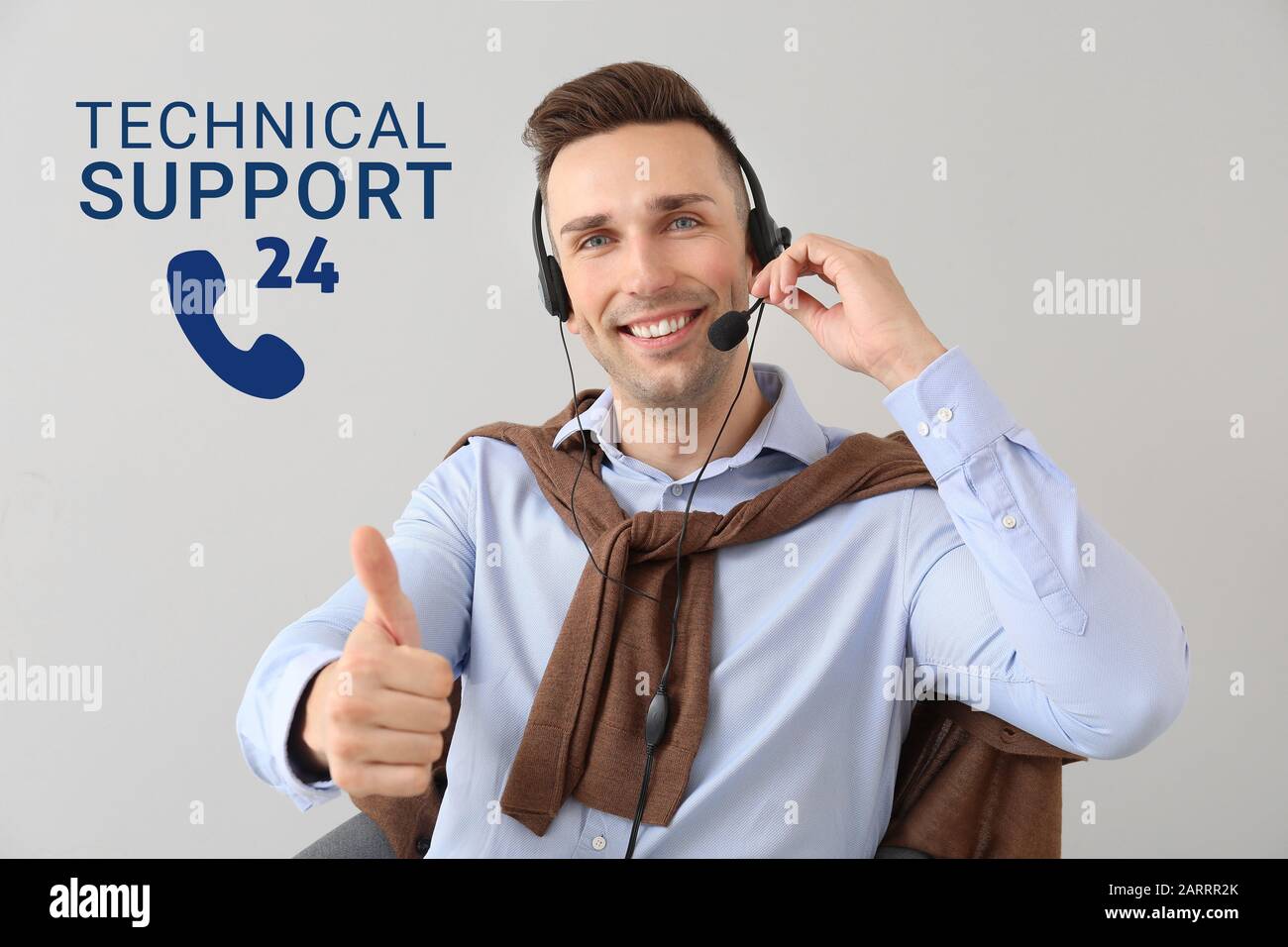 Male technical support agent showing thumb-up gesture on light ...