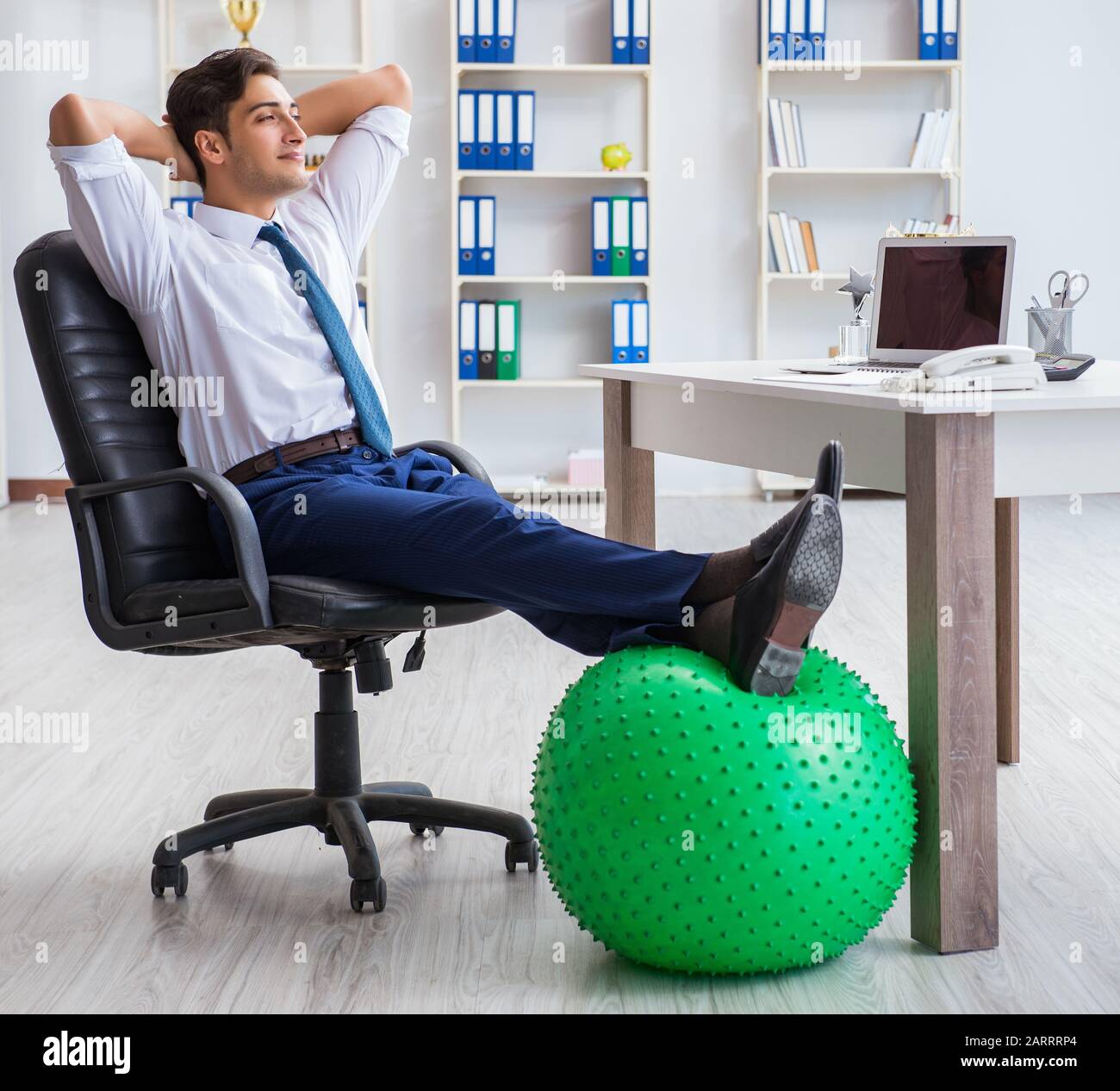 The young businessman doing sports stretching at workplace Stock Photo ...
