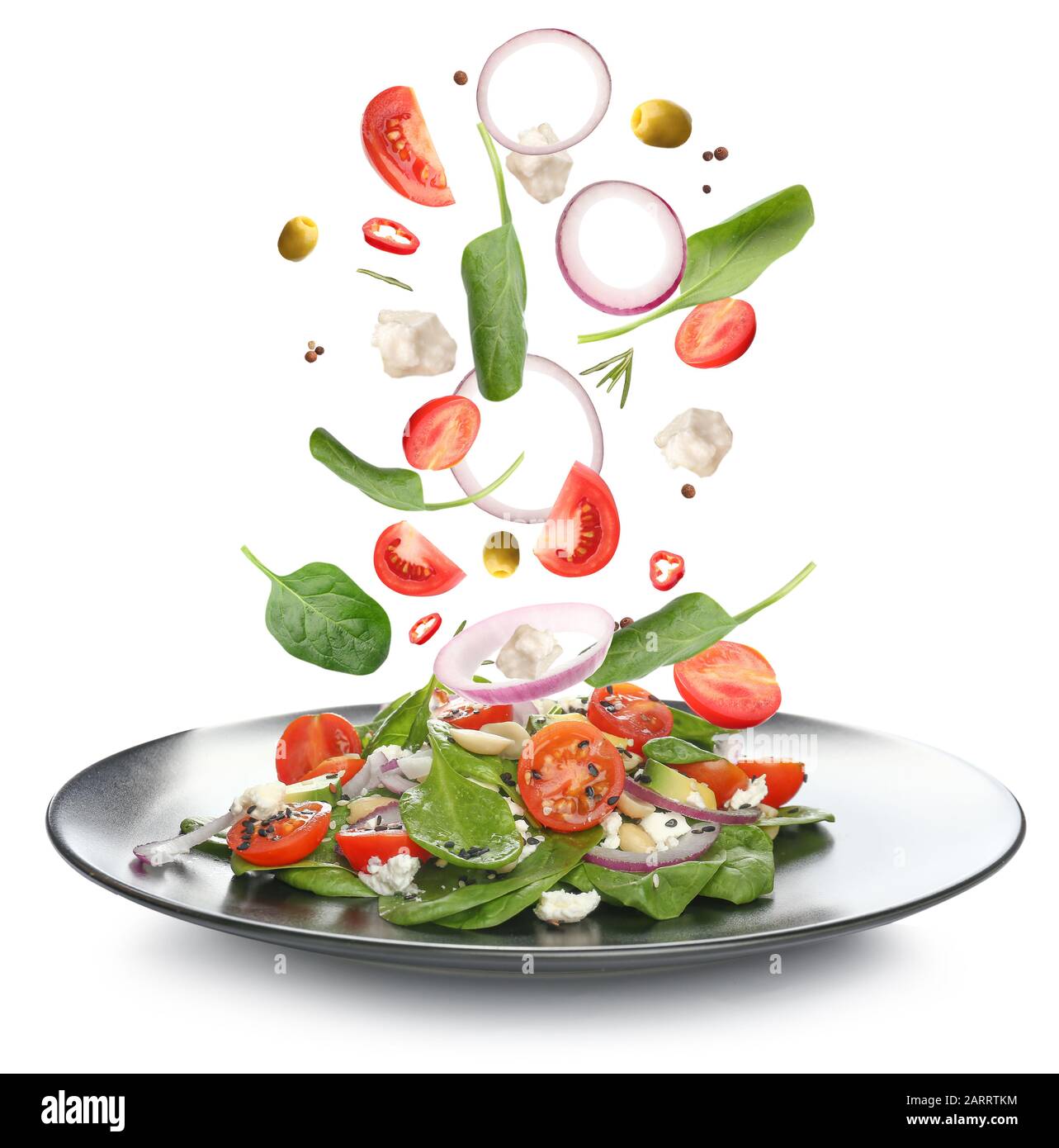 Plate with fresh salad and falling ingredients on white background ...
