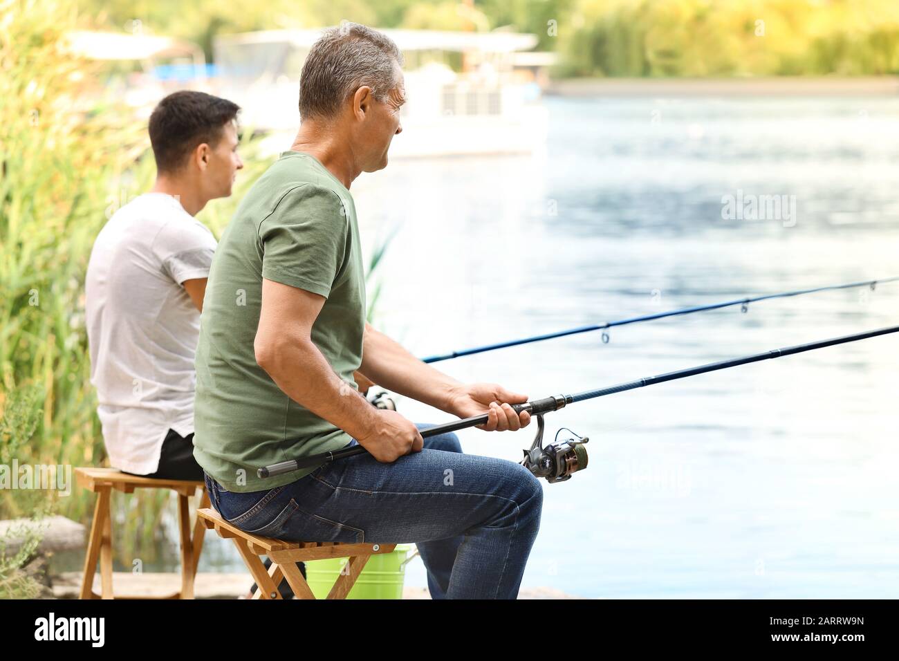 Young man and his father fishing on river Stock Photo - Alamy