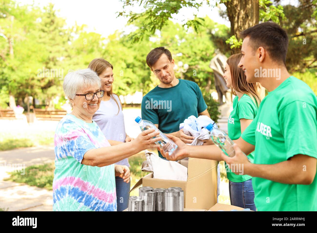 Young volunteers giving donation to poor people outdoors Stock Photo ...