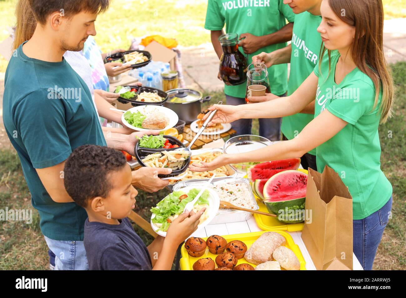 Young volunteers giving food to poor people outdoors Stock Photo - Alamy
