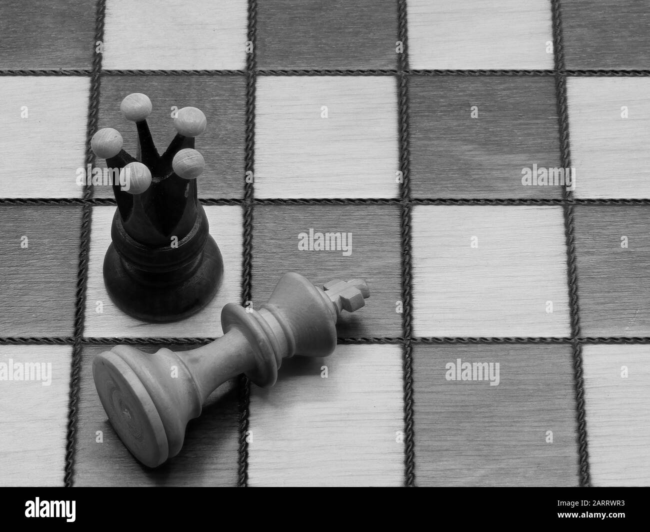 Checkmate: A Black Queen Next To A Defeated White King On A Wooden ...