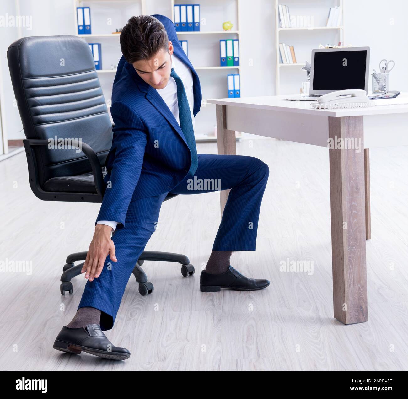 The young businessman doing sports stretching at workplace Stock Photo ...