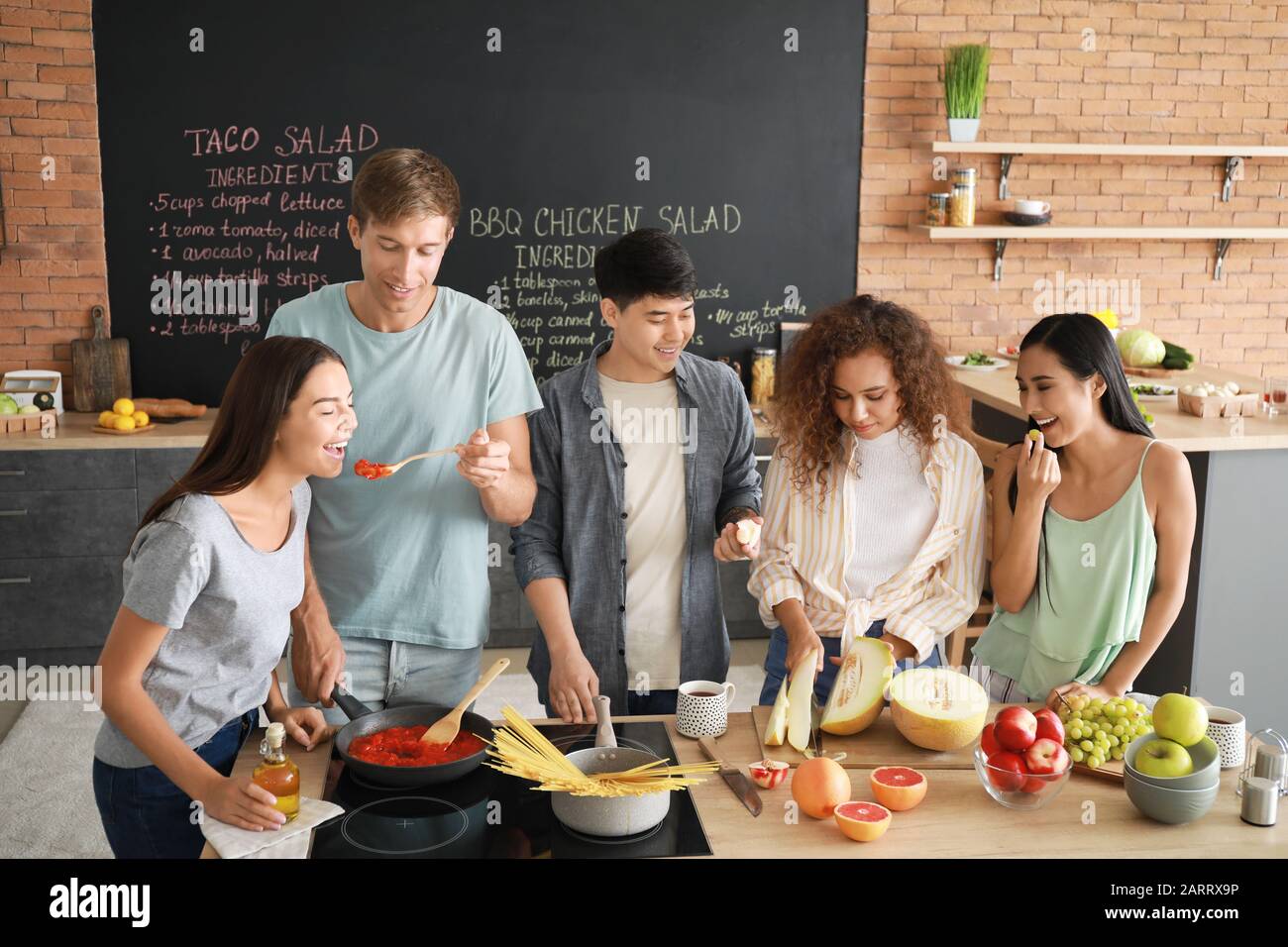 Happy friends cooking together in kitchen Stock Photo - Alamy