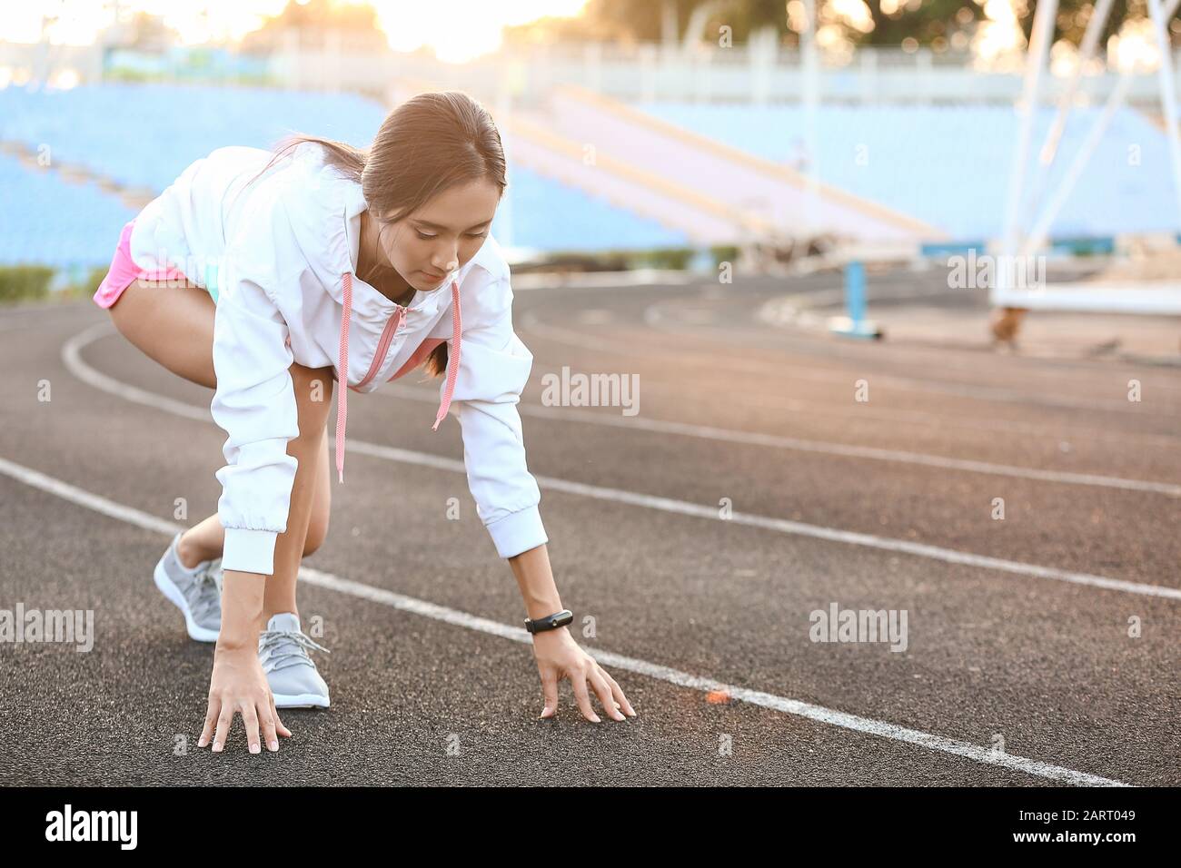 Sporty Asian woman in crouch start position at the stadium Stock Photo ...