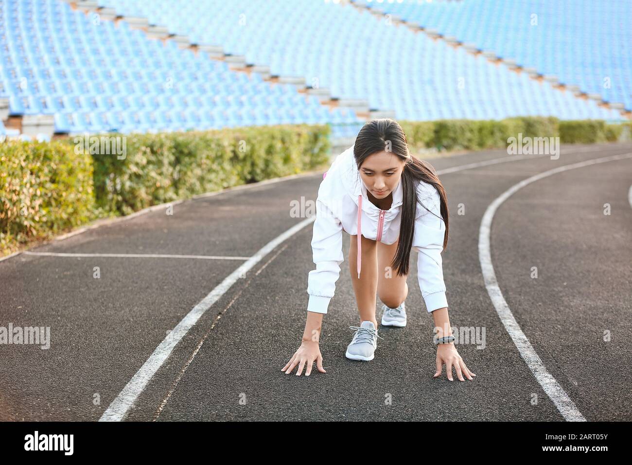 Sporty Asian woman in crouch start position at the stadium Stock Photo ...