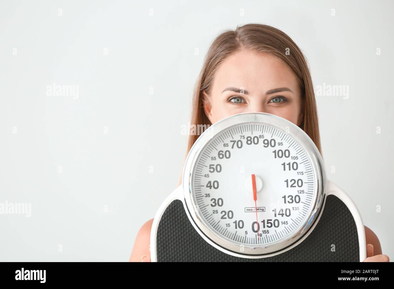 Beautiful young woman with scales on light background. Weight loss ...