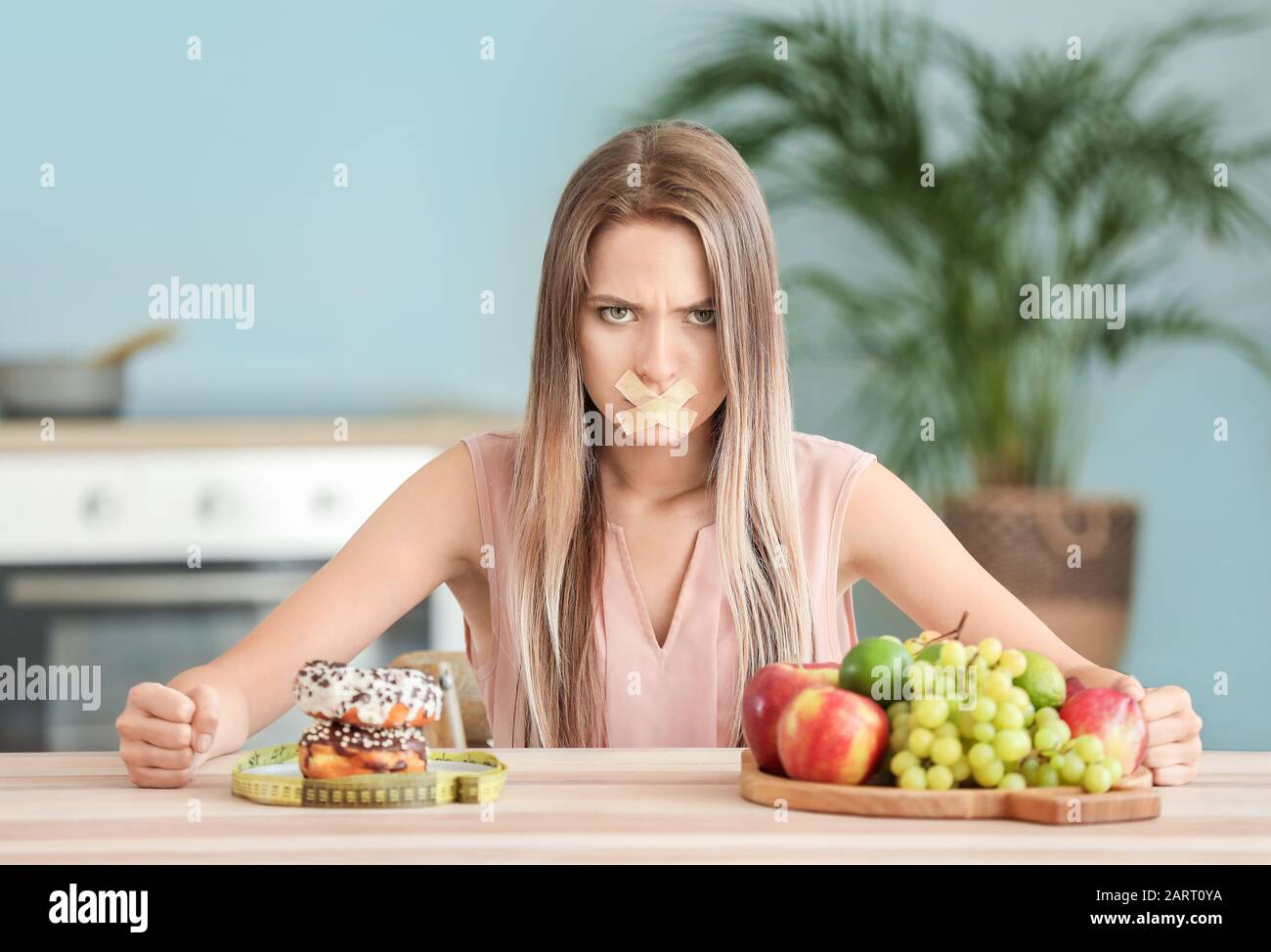 Angry woman with taped mouth, healthy and unhealthy food in kitchen ...