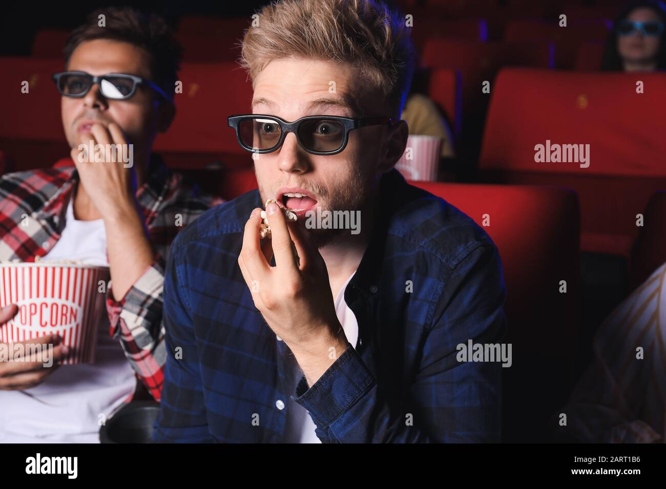 Young man with popcorn watching movie in cinema Stock Photo - Alamy