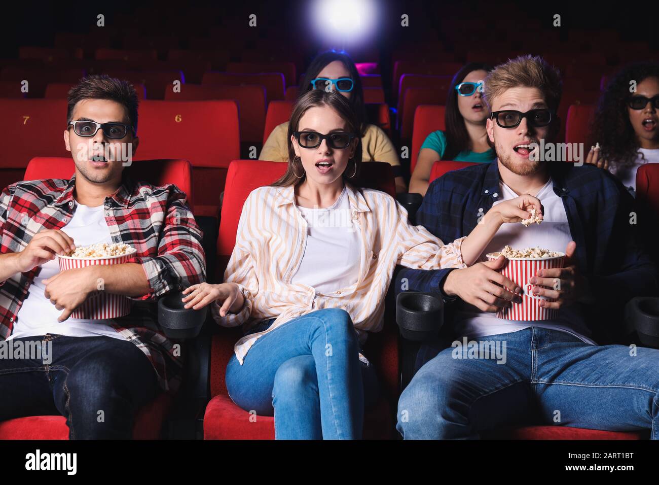 Friends with popcorn watching movie in cinema Stock Photo - Alamy