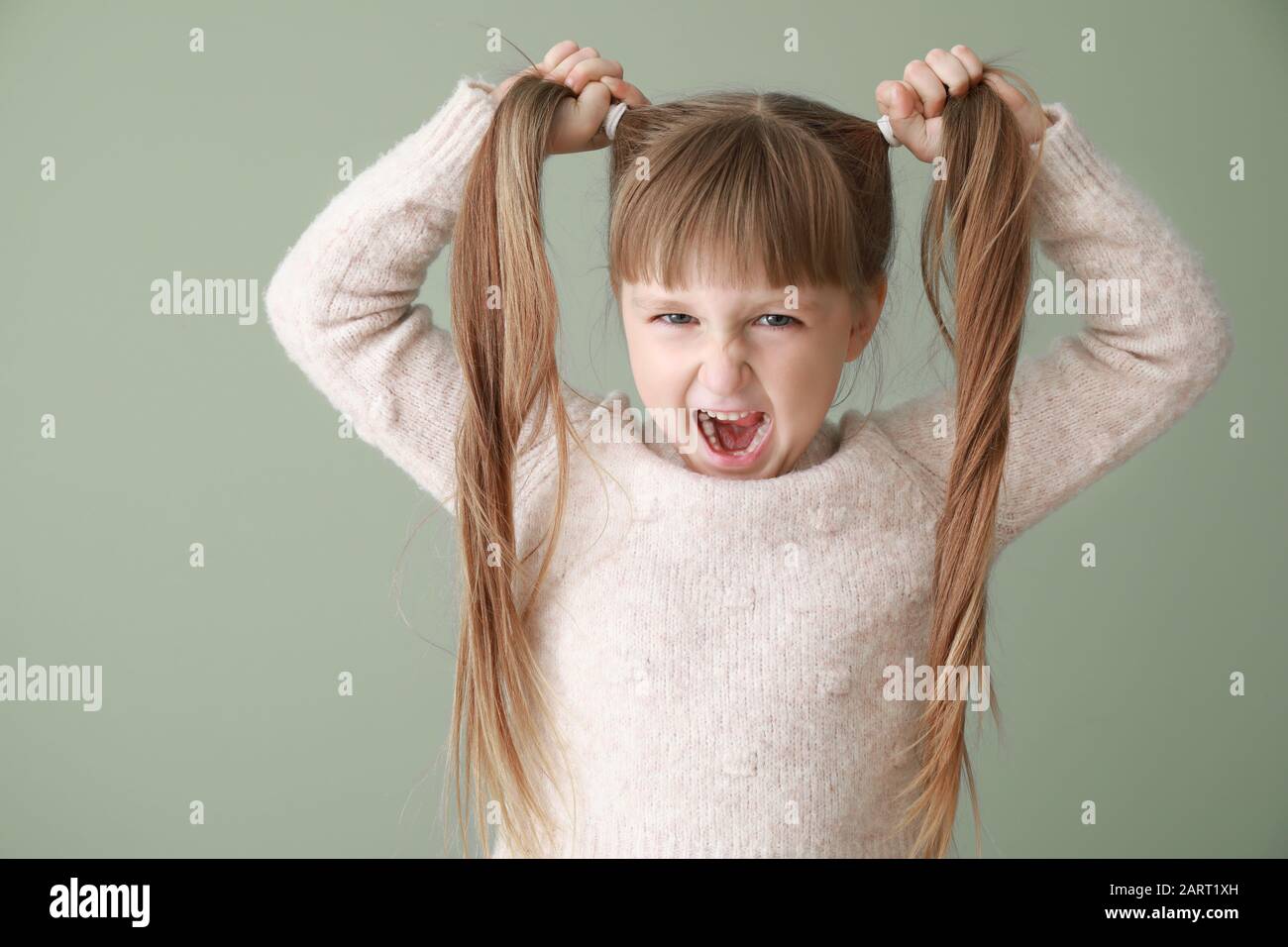 Portrait of angry little girl on color background Stock Photo - Alamy