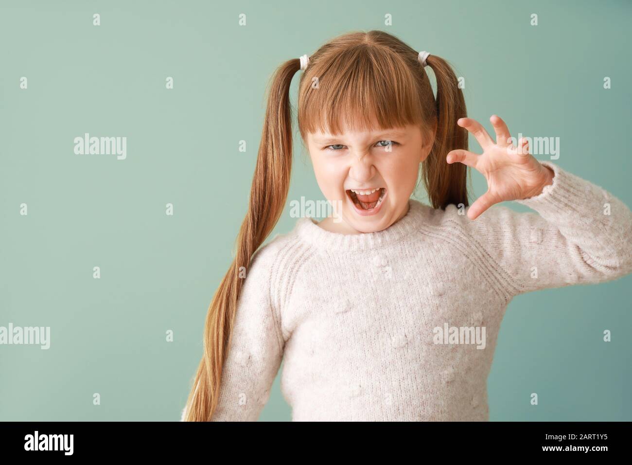 Portrait of angry little girl on color background Stock Photo - Alamy