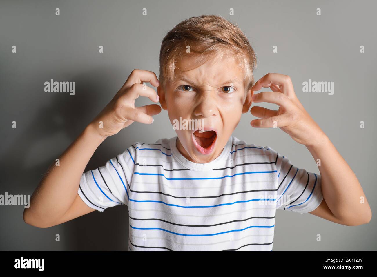 Portrait of angry little boy on grey background Stock Photo - Alamy