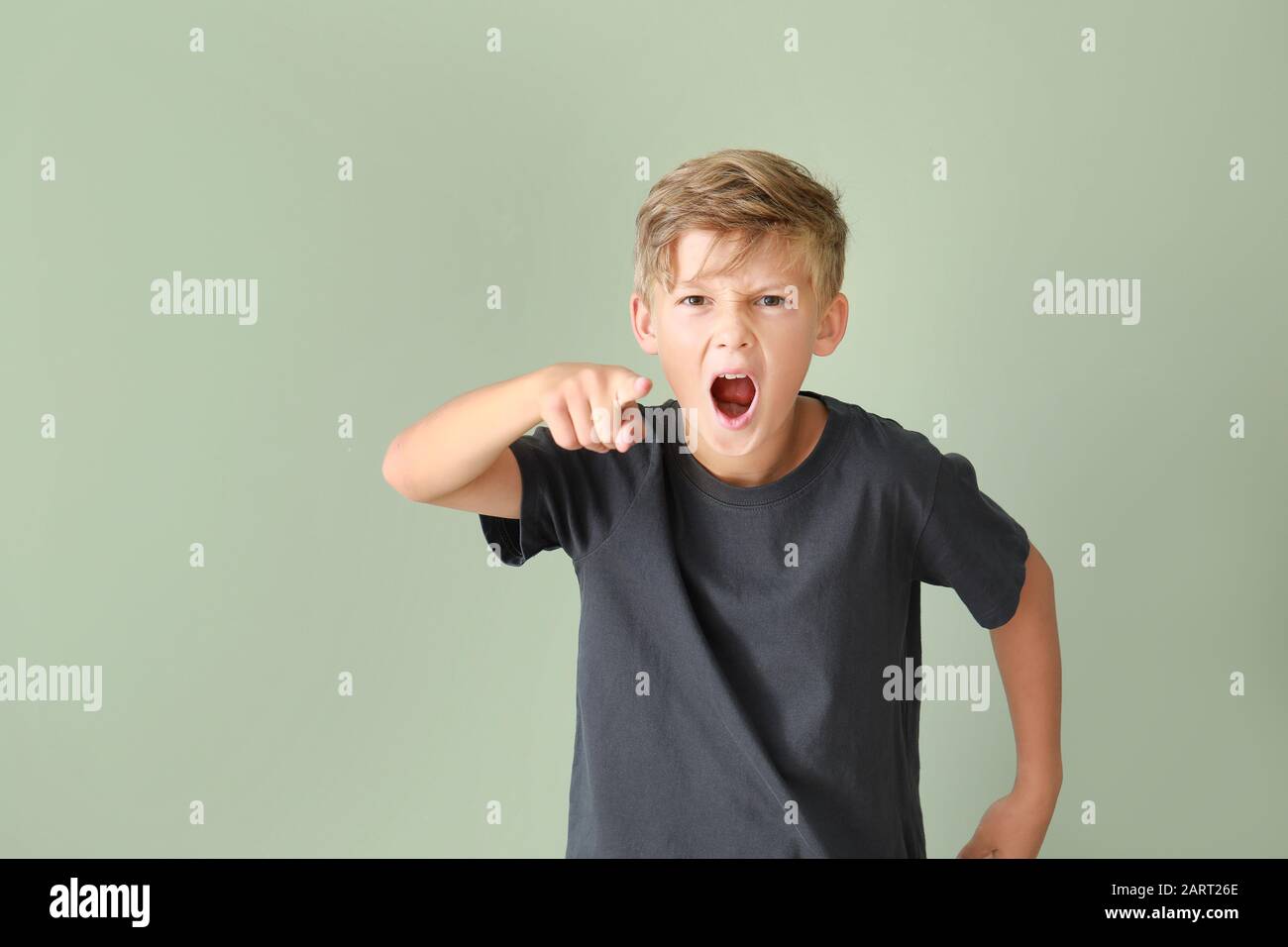Portrait of angry little boy on color background Stock Photo - Alamy