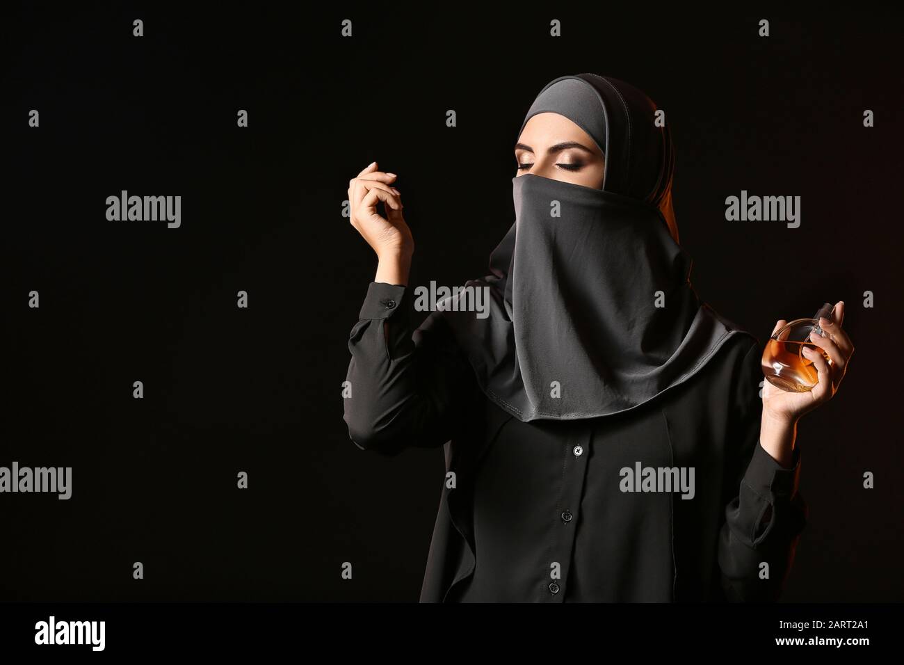 Beautiful Muslim woman with perfume on dark background Stock Photo - Alamy