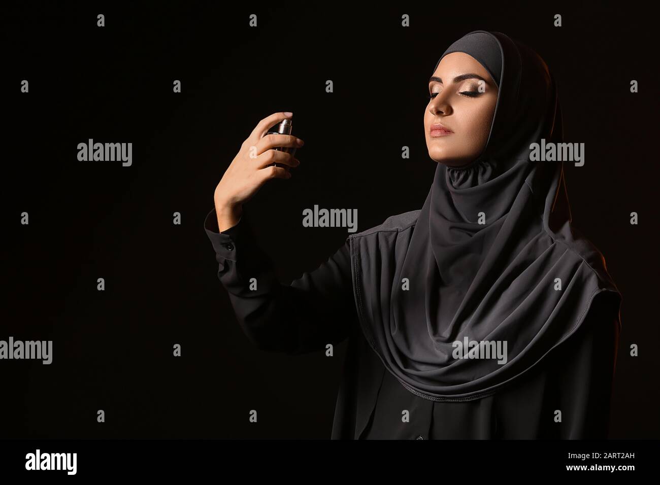 Beautiful Muslim woman with perfume on dark background Stock Photo - Alamy